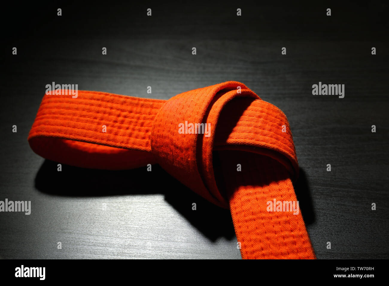 Orange karate belt on dark background Stock Photo - Alamy