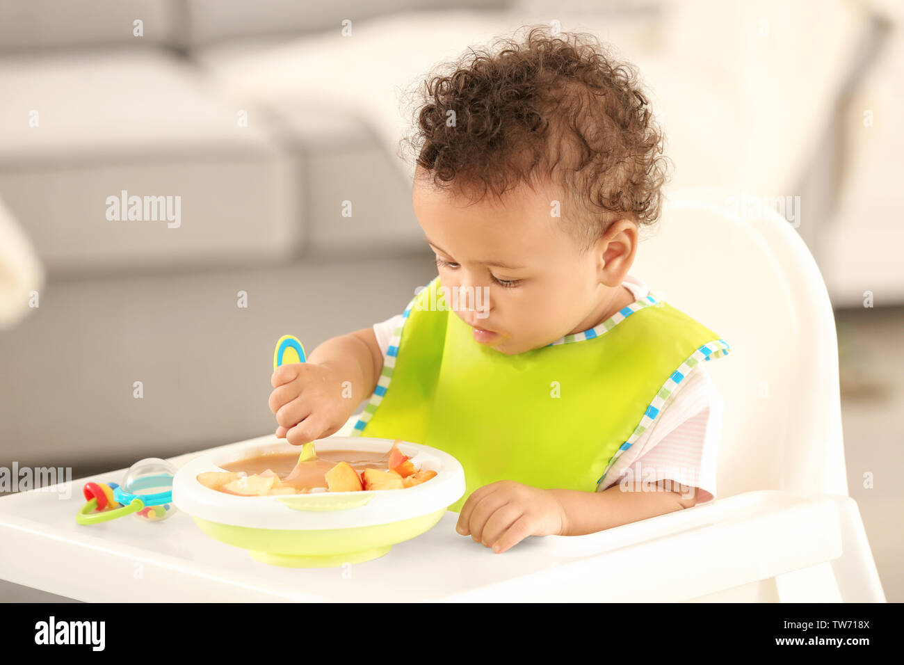 Little baby eating fruit puree indoors Stock Photo - Alamy