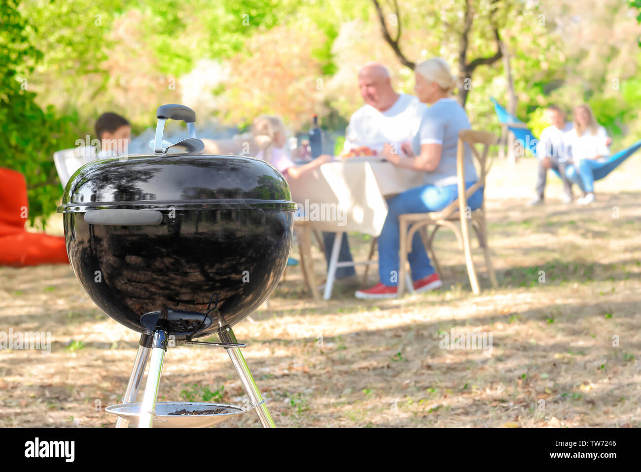 Barbecue grill and happy family on background outdoors Stock Photo - Alamy