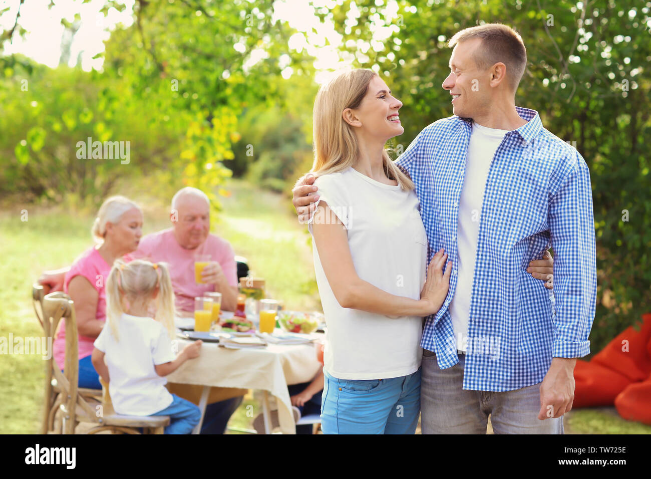 Happy couple with family having barbecue party outdoors Stock Photo - Alamy
