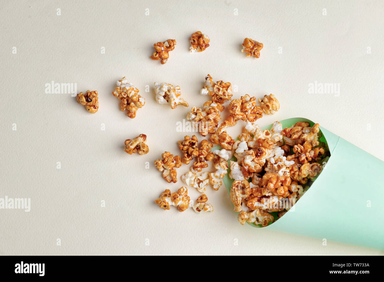 Paper cone with tasty caramel popcorn on light background Stock Photo ...