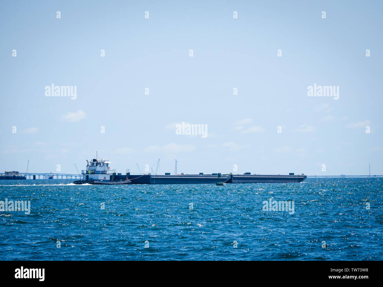 Barge being pushed by a tugboat in tropical blue ocean water. Freight ...