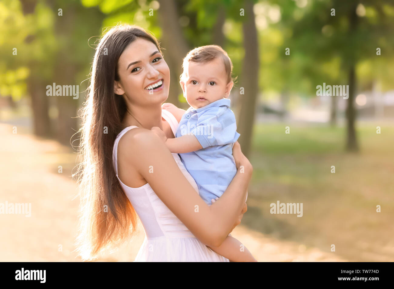 Beautiful young mother holding cute baby boy, outdoors Stock Photo - Alamy