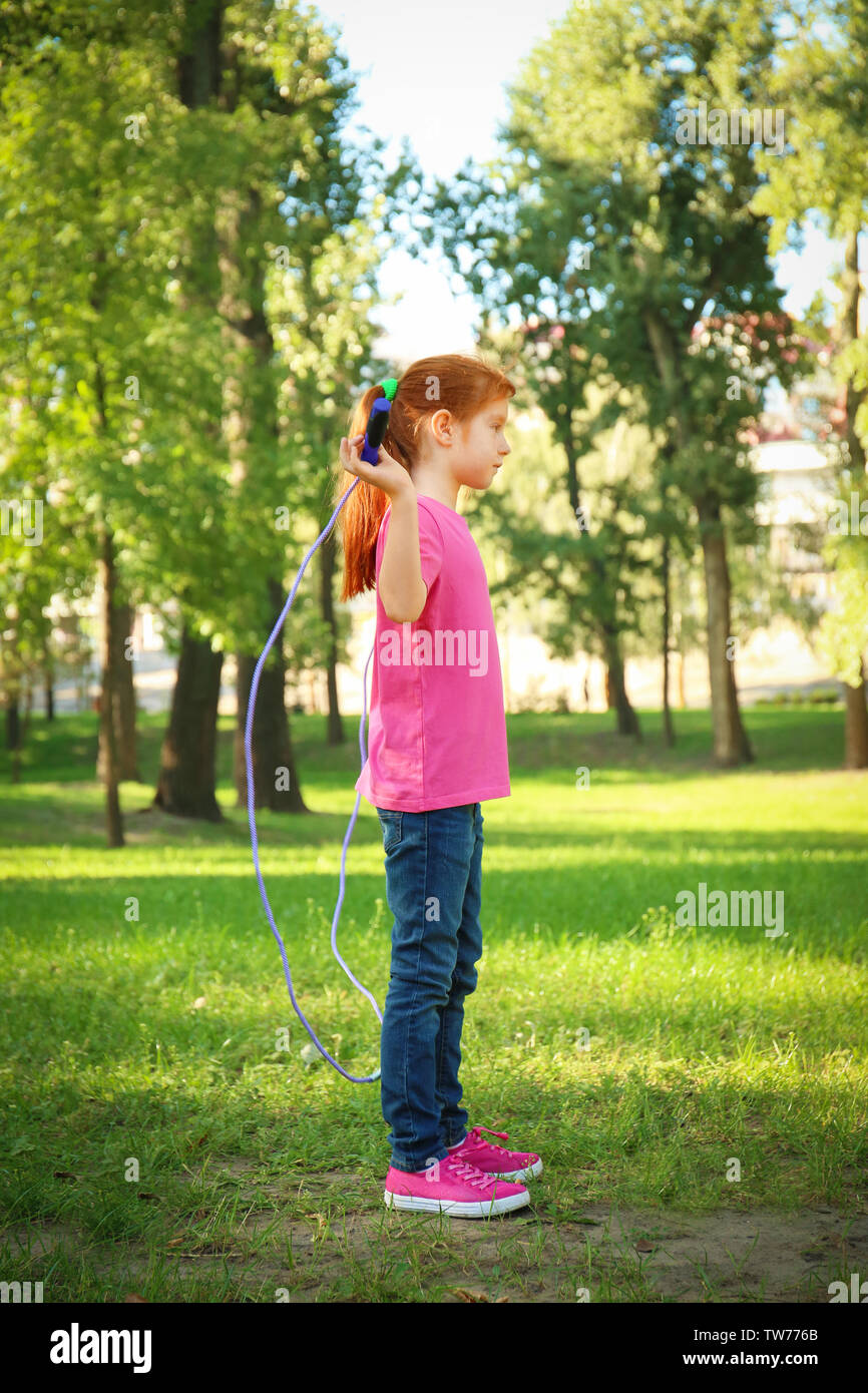 Cute little girl jumping rope in park Stock Photo - Alamy