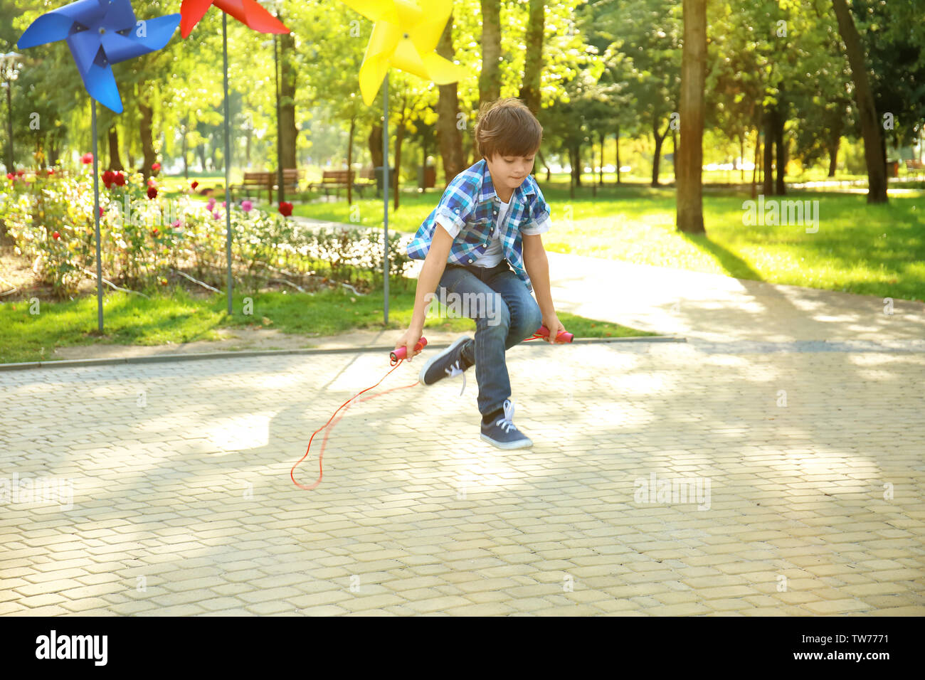 Cute little boy jumping rope in park Stock Photo - Alamy