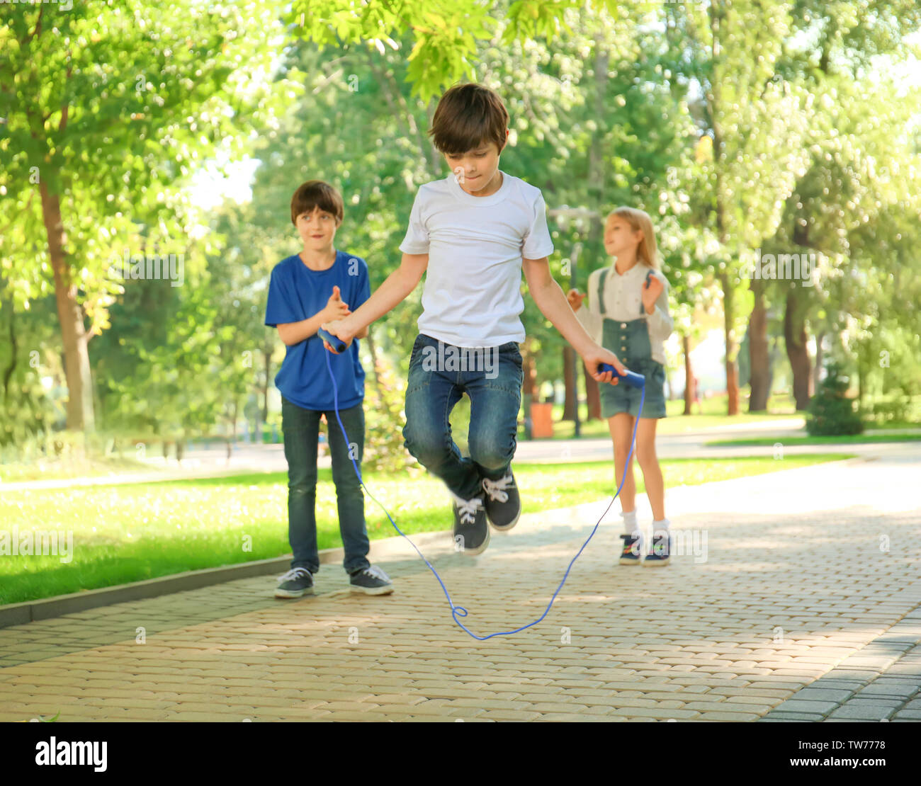 Cute little children jumping rope in park Stock Photo - Alamy