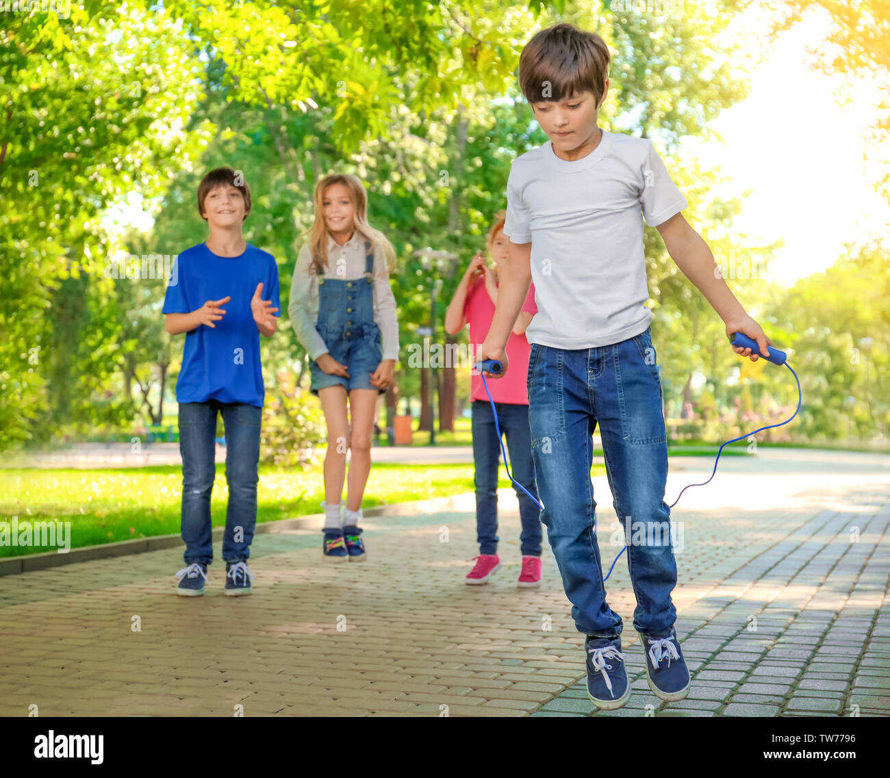 Cute little children jumping rope in park Stock Photo - Alamy