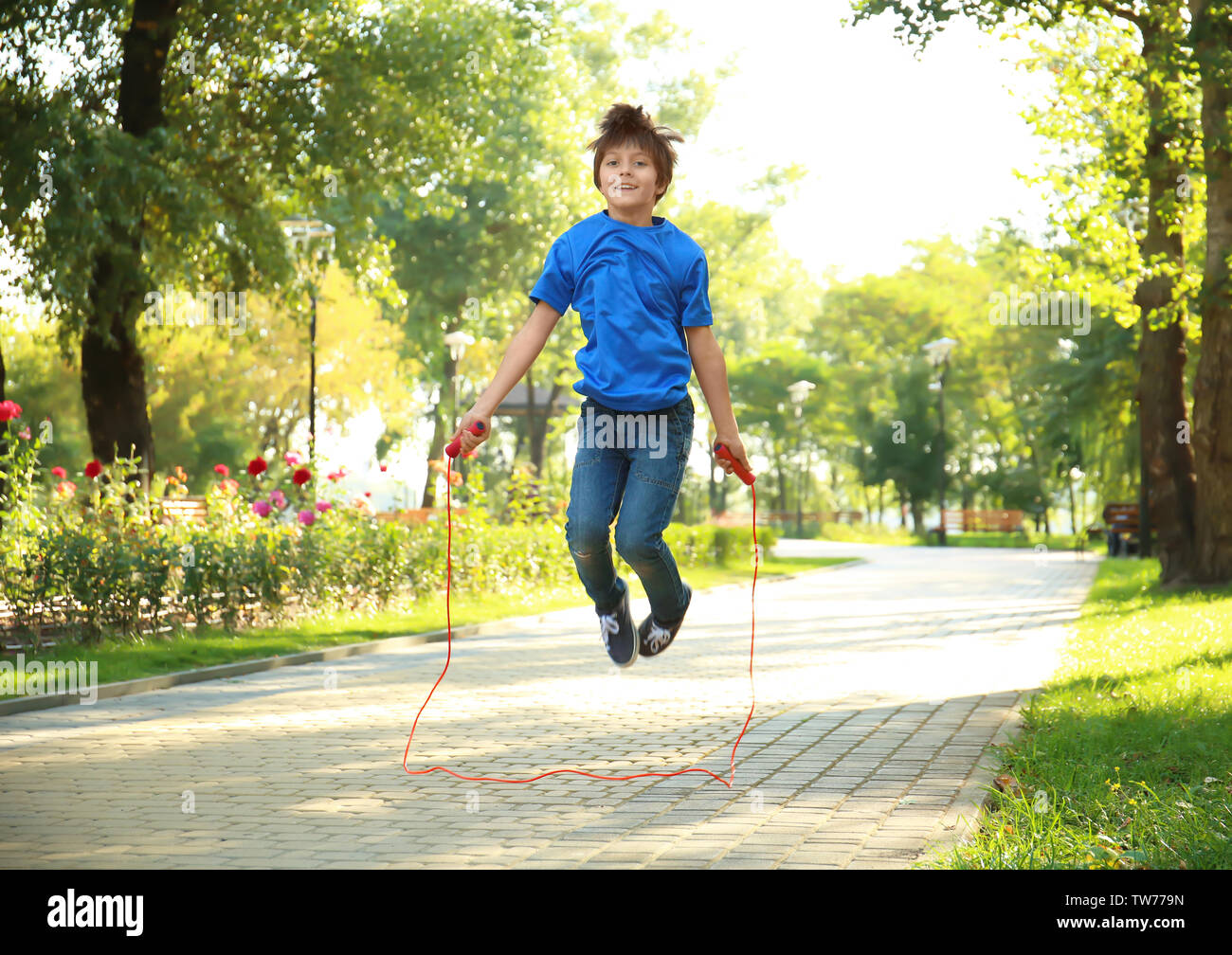 Cute little boy jumping rope in park Stock Photo - Alamy