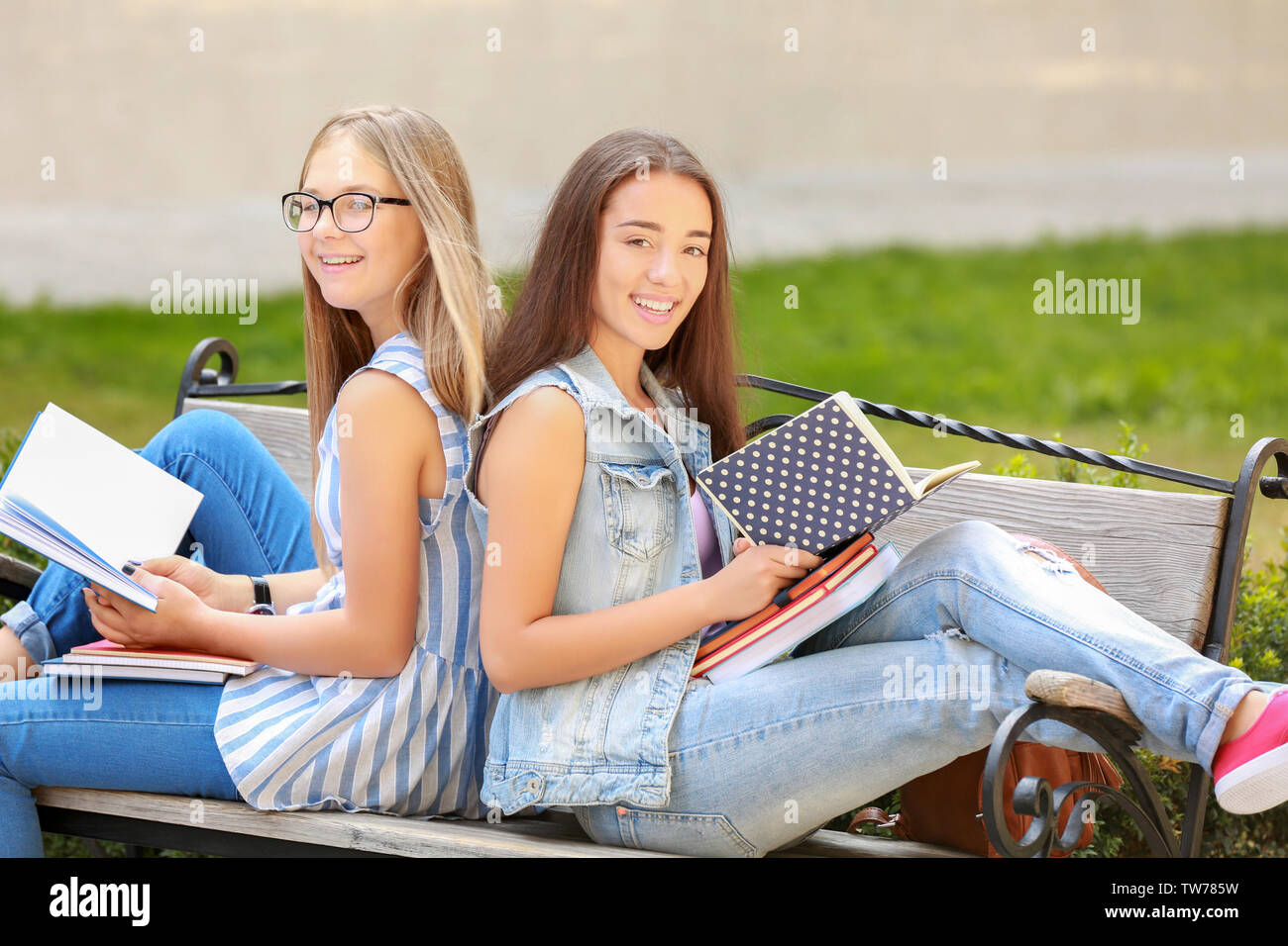 Pretty students studying while sitting on bench outdoors Stock Photo ...