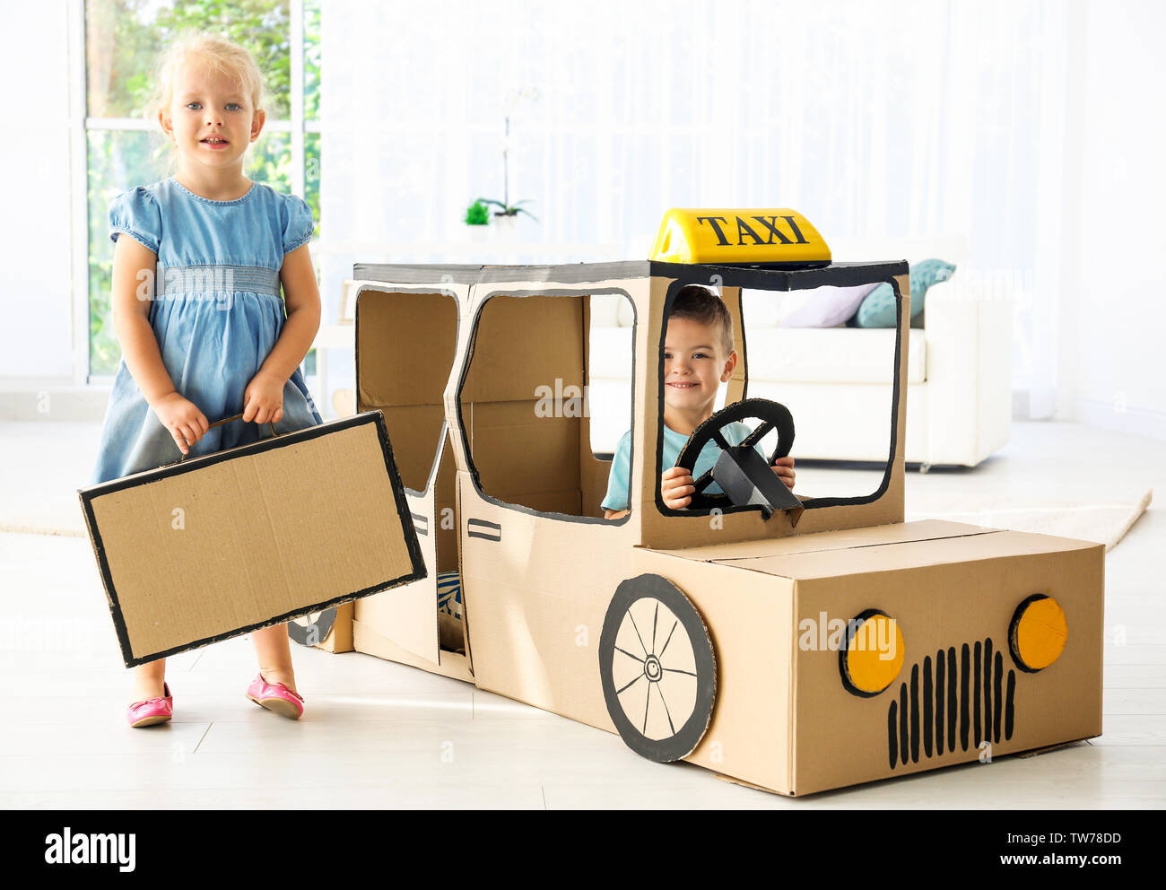 Little children playing with cardboard taxi in light room Stock Photo ...