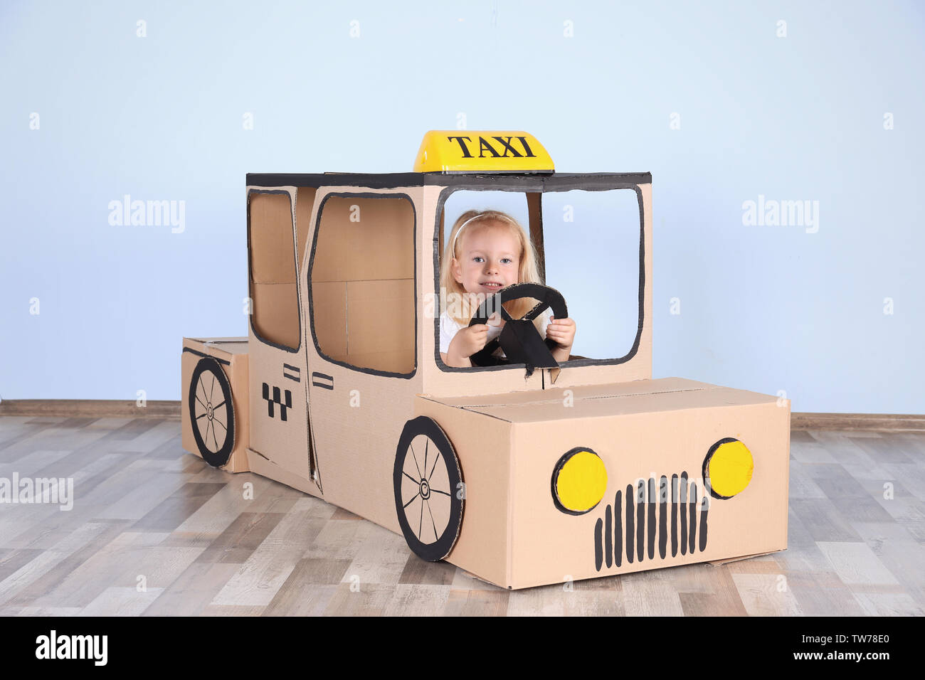 Little girl playing with cardboard taxi in light room Stock Photo - Alamy
