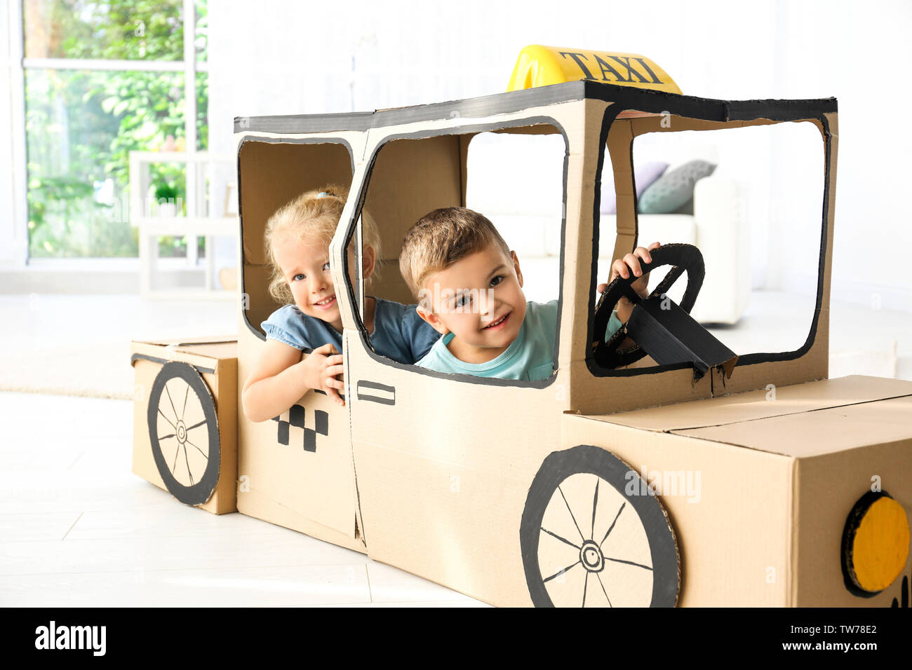 Little children playing with cardboard taxi in light room Stock Photo ...