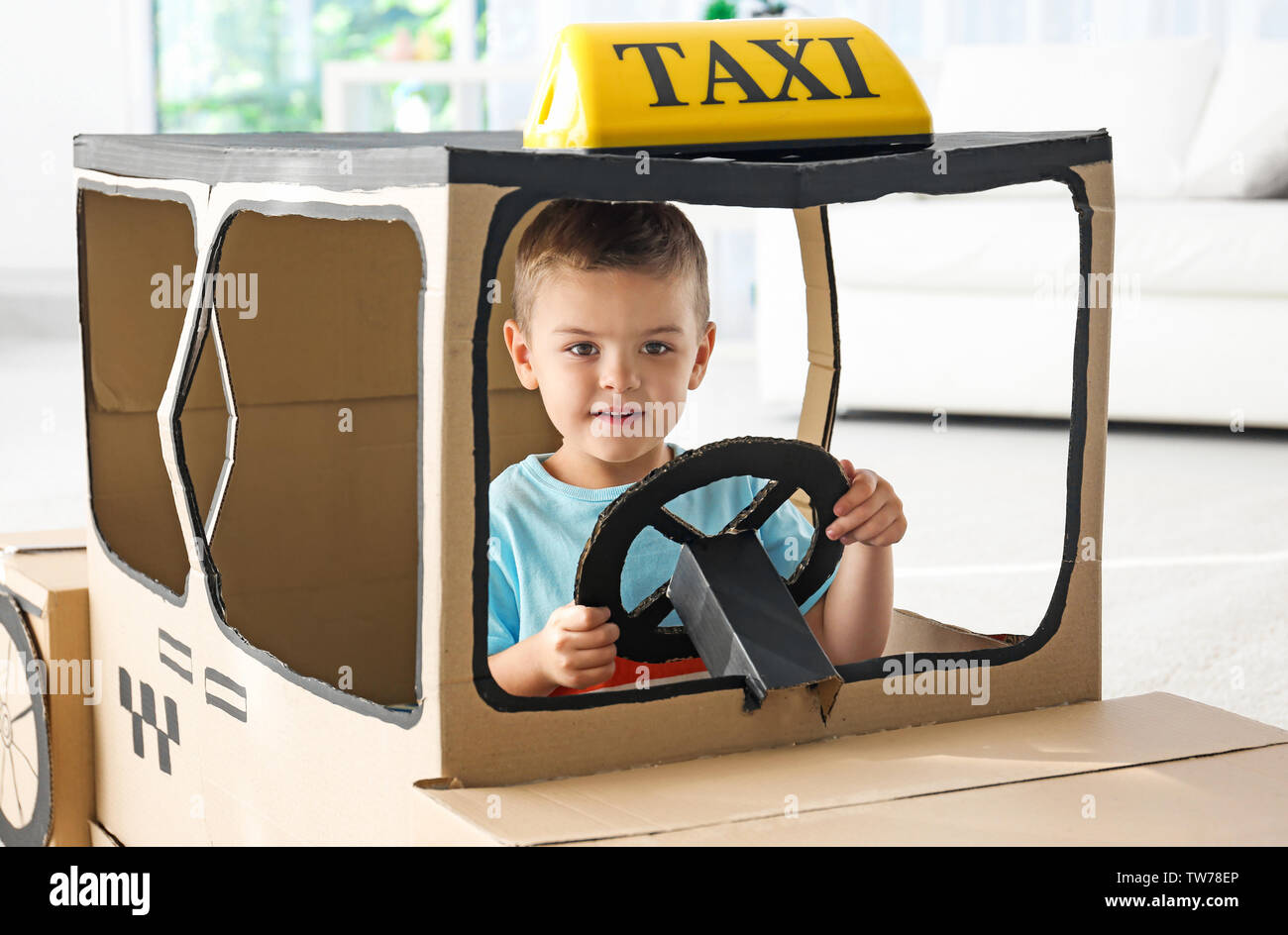 Little boy playing with cardboard taxi in light room Stock Photo - Alamy