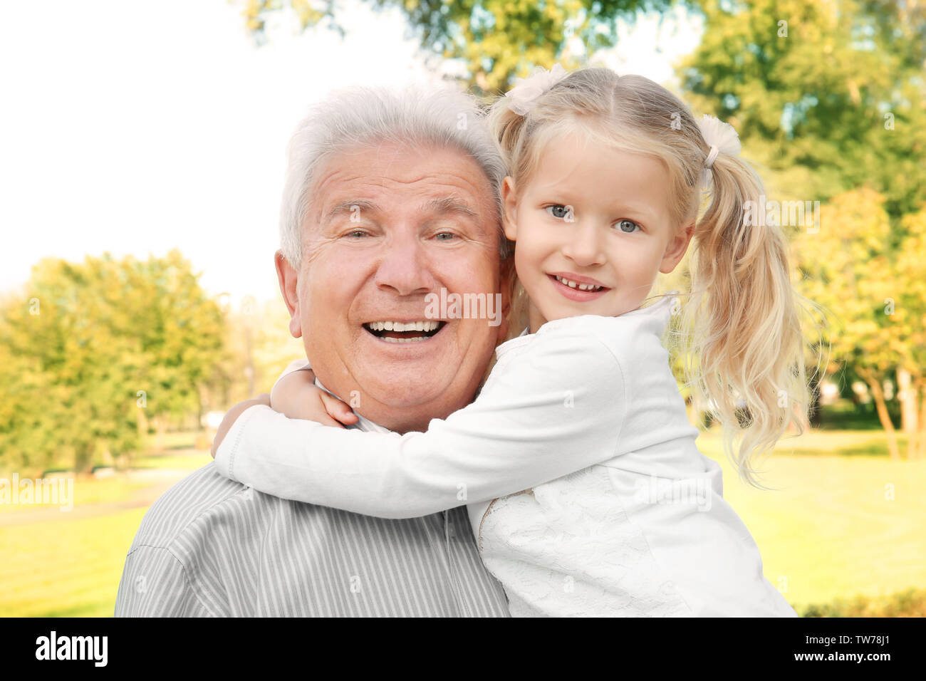 Cute little girl hugging grandfather in park Stock Photo - Alamy