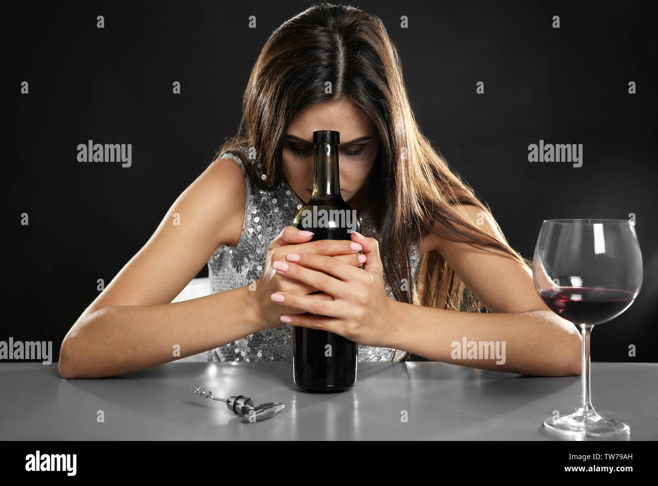 Young woman drinking alcohol at table against black background Stock ...