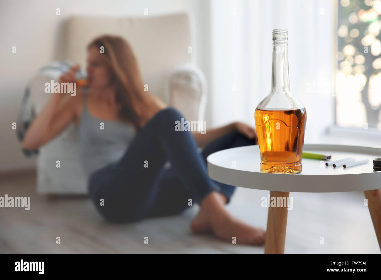 Bottle with alcohol on table and drunk woman on background Stock Photo ...