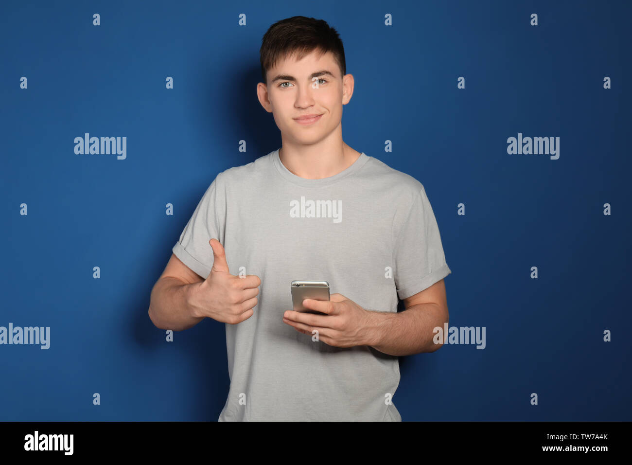 Trendy teenage boy using mobile phone on color background Stock Photo ...