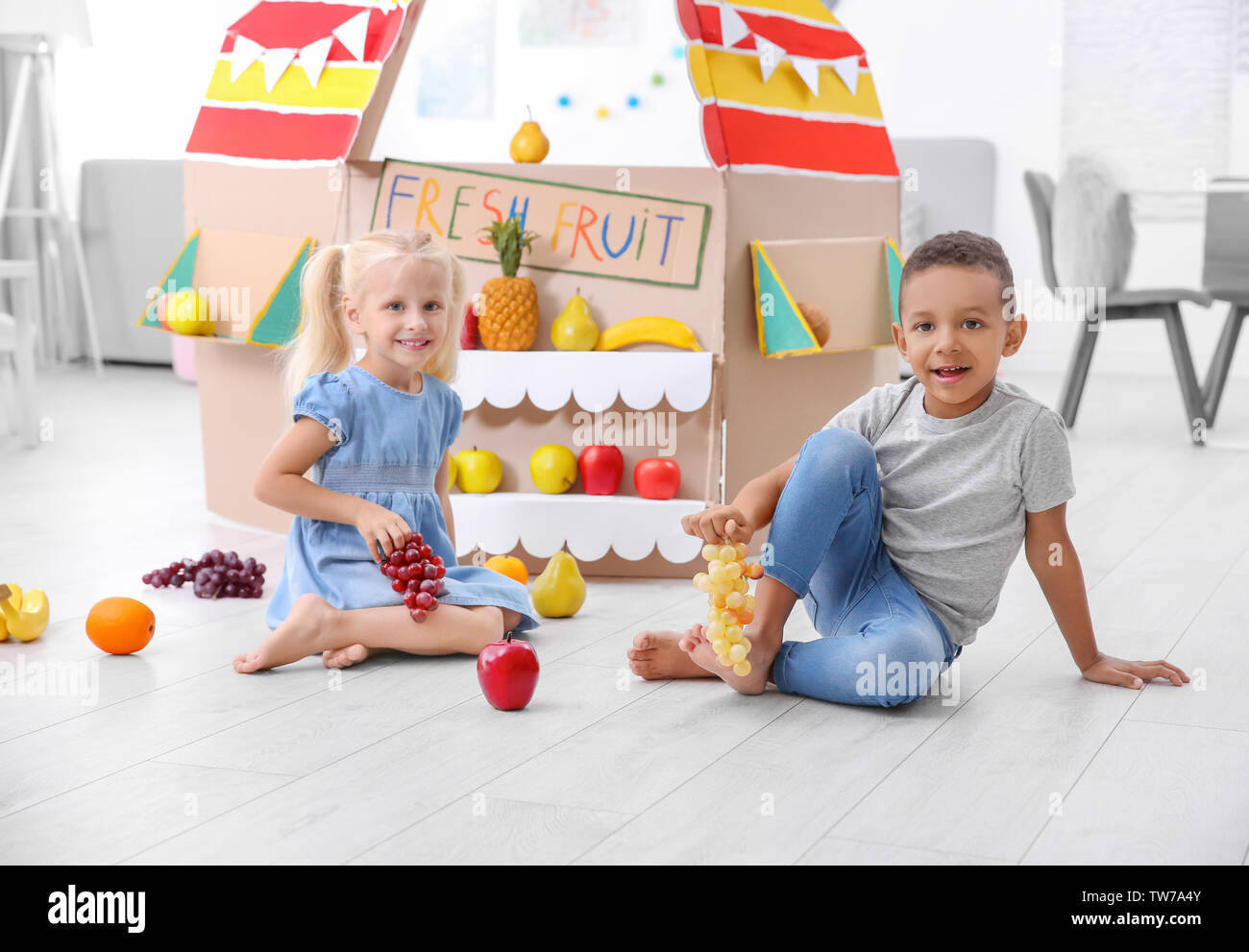 Cute kids sitting near counter with fruits indoors Stock Photo - Alamy