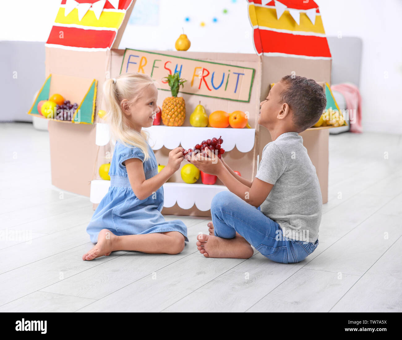 Cute kids sitting near counter with fruits indoors Stock Photo - Alamy