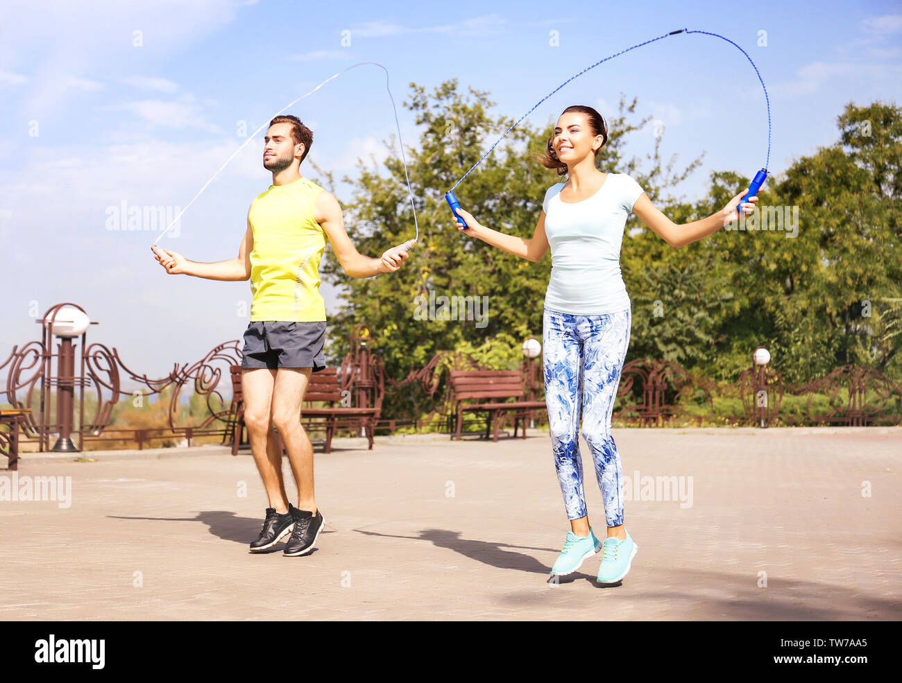 Young man and woman with jumping ropes in park Stock Photo - Alamy