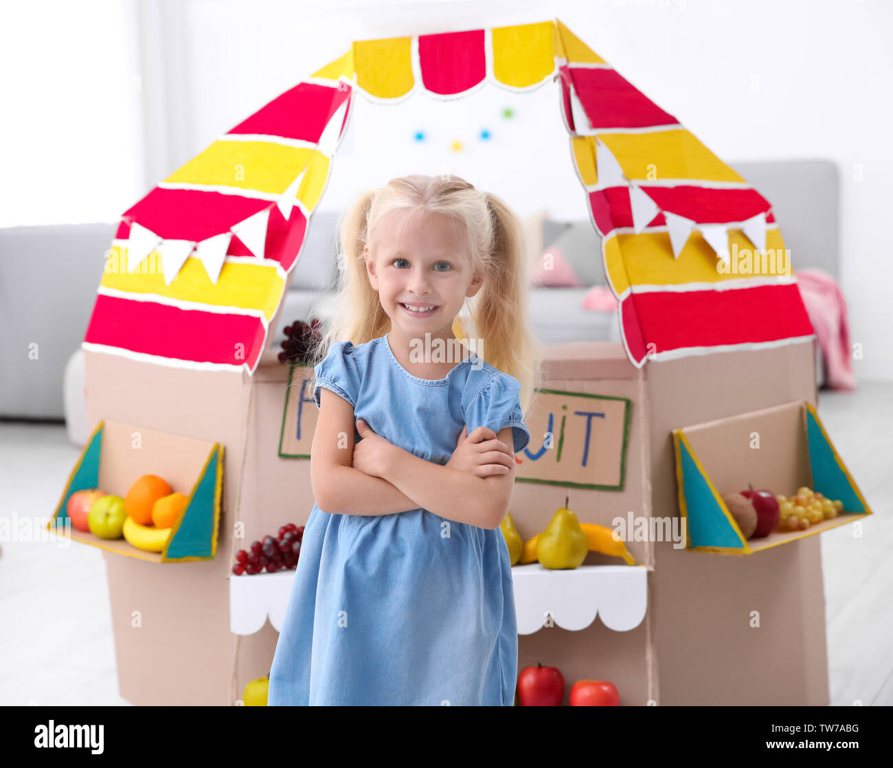Cute little girl standing near counter with fruits indoors Stock Photo ...