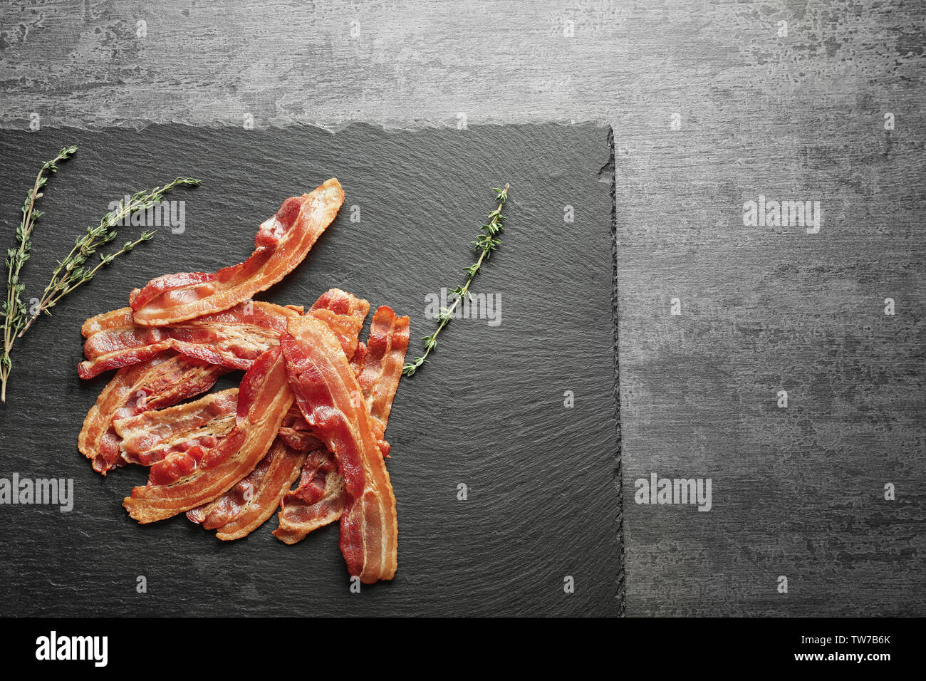 Slate plate with cooked bacon rashers on table Stock Photo - Alamy