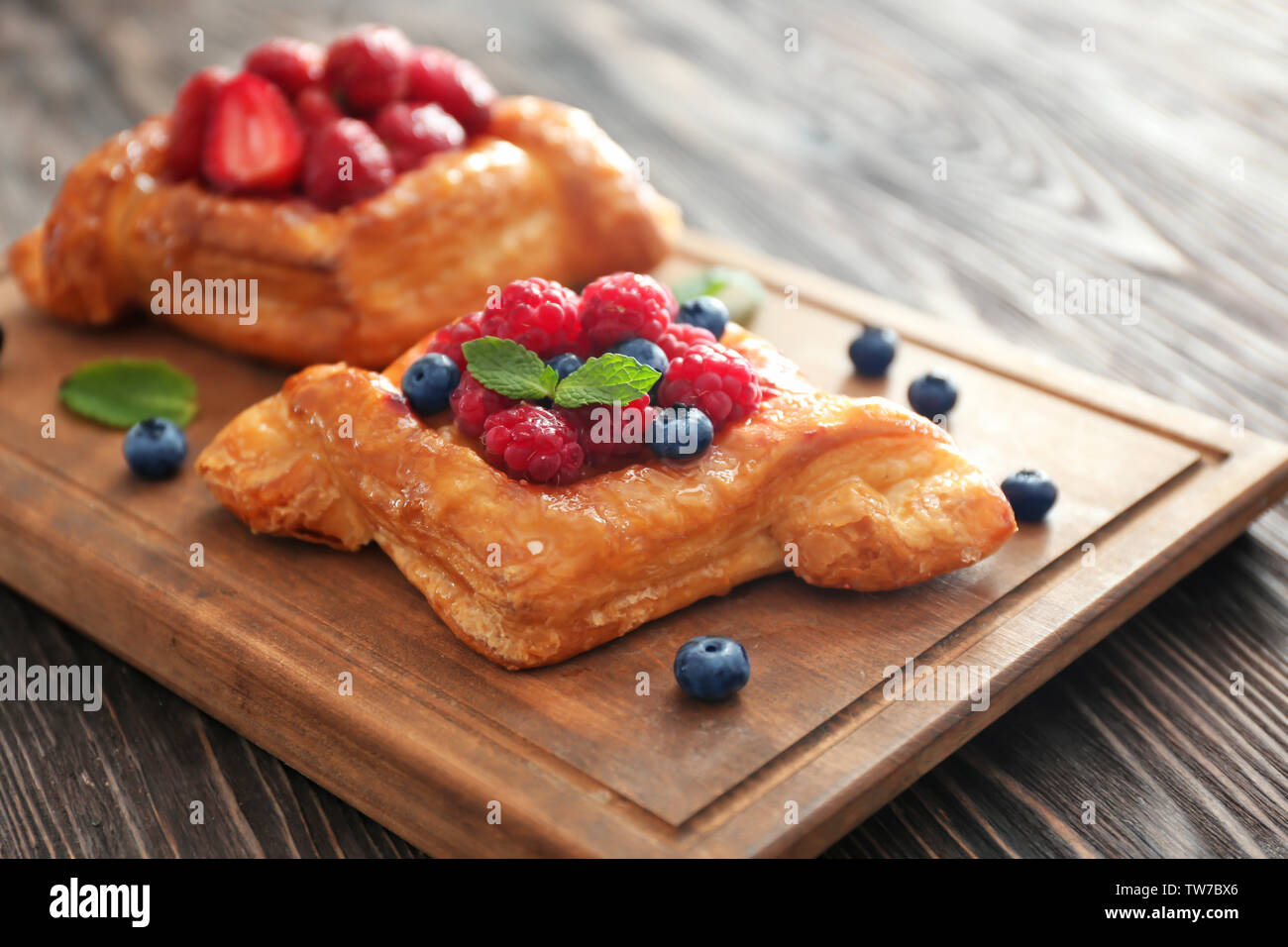 Board with tasty berry pastries on table Stock Photo - Alamy