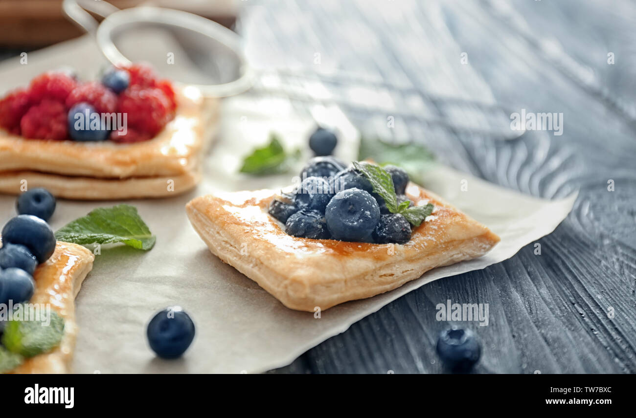 Parchment with tasty berry pastries on table Stock Photo - Alamy