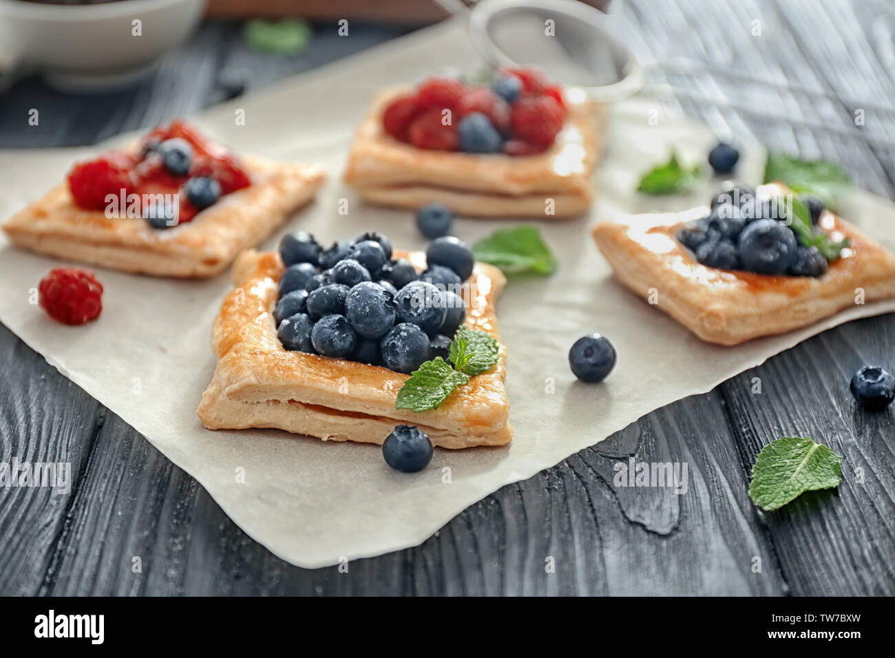 Parchment with tasty berry pastries on table Stock Photo - Alamy