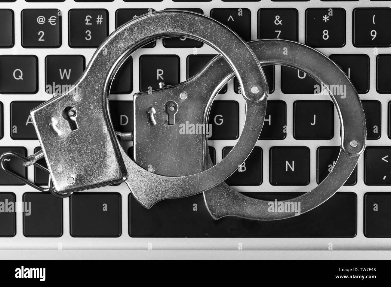 Handcuffs on laptop keyboard, close up Stock Photo - Alamy