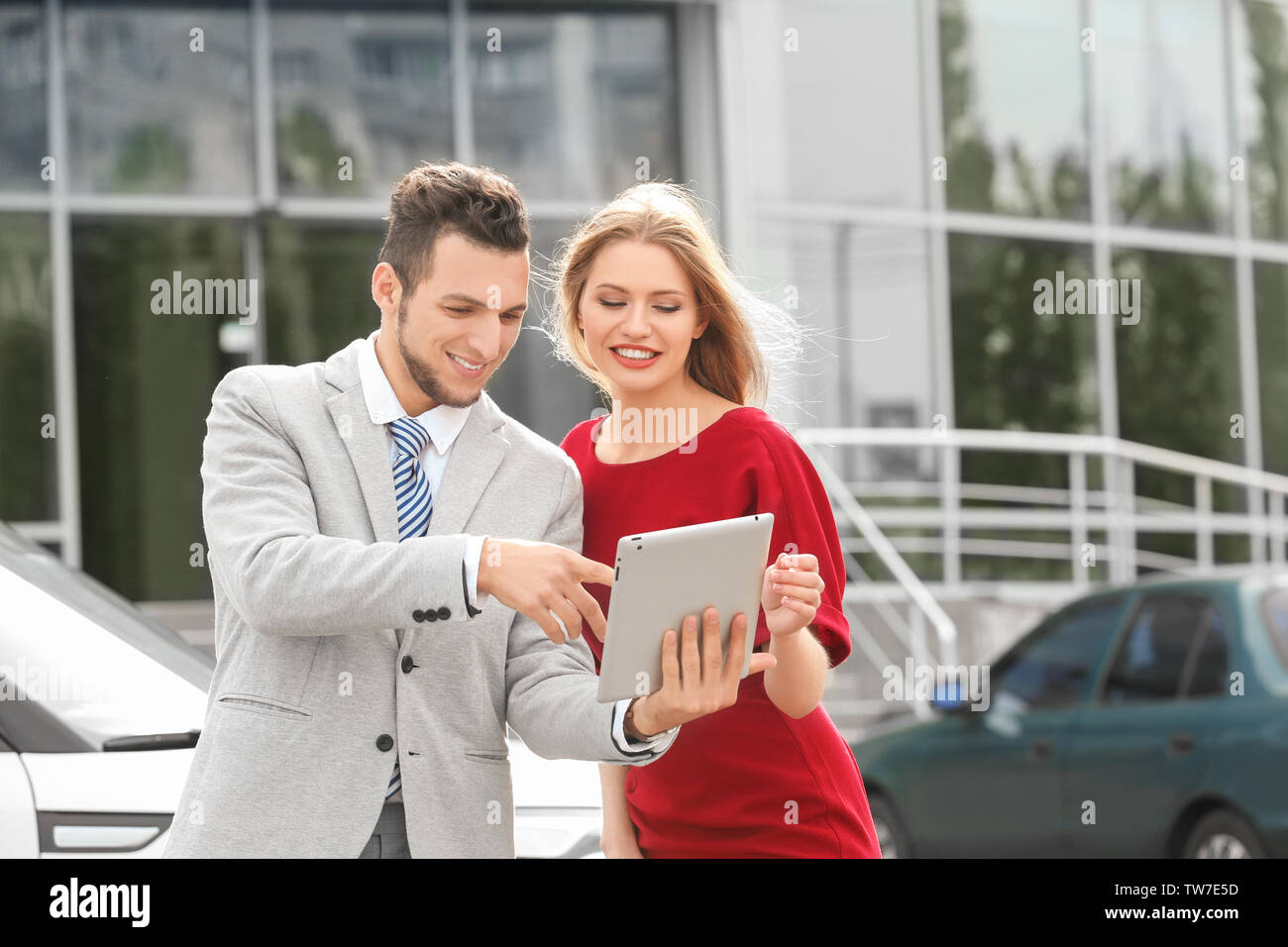 Salesman with tablet and client standing near new car outdoors Stock ...