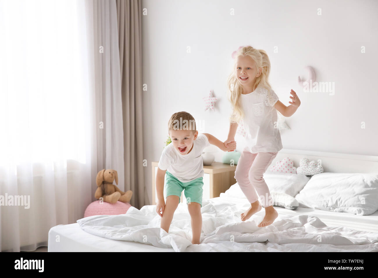 Cute little children jumping on bed at home Stock Photo - Alamy