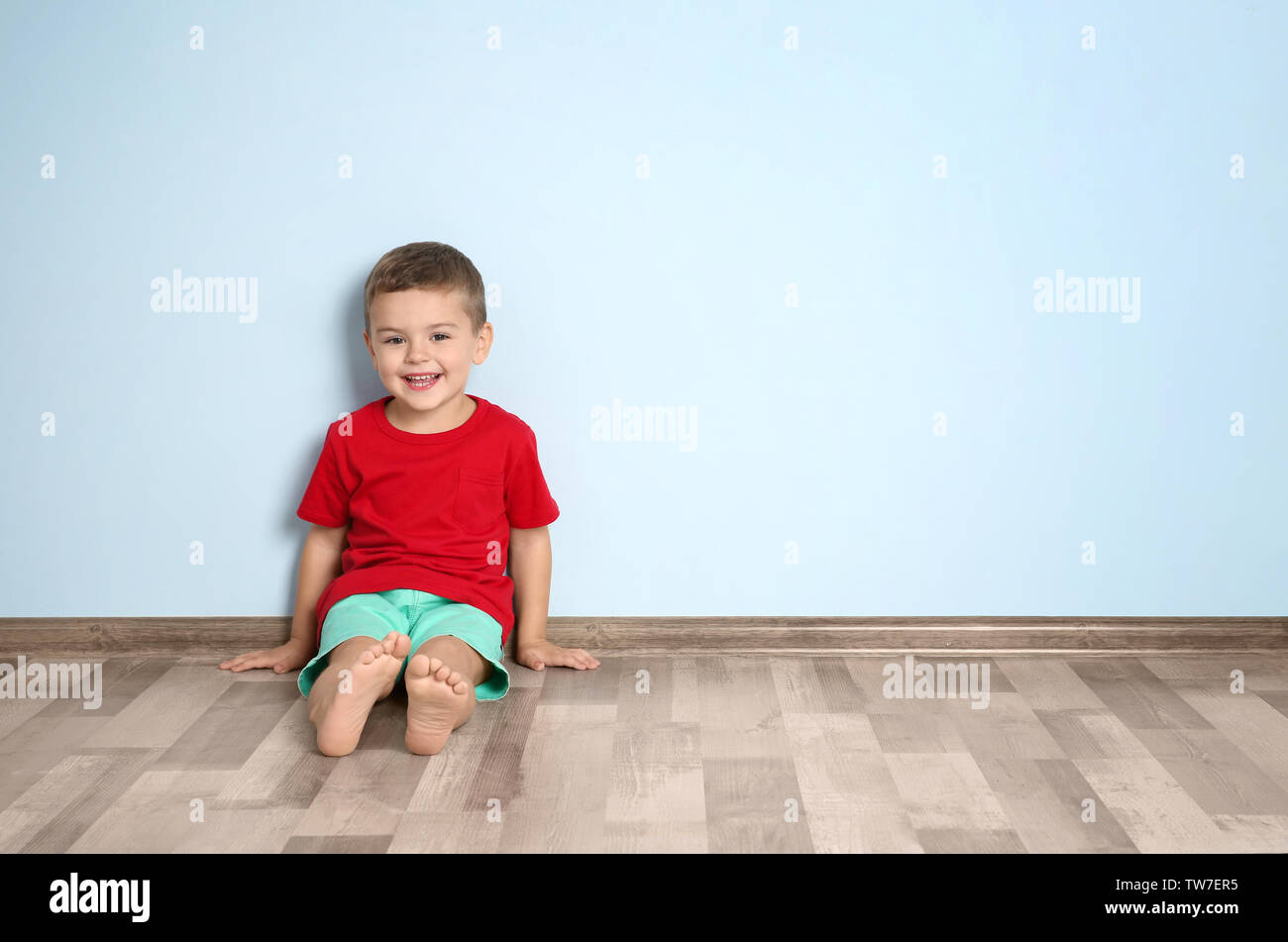 Cute little boy sitting near color wall Stock Photo - Alamy