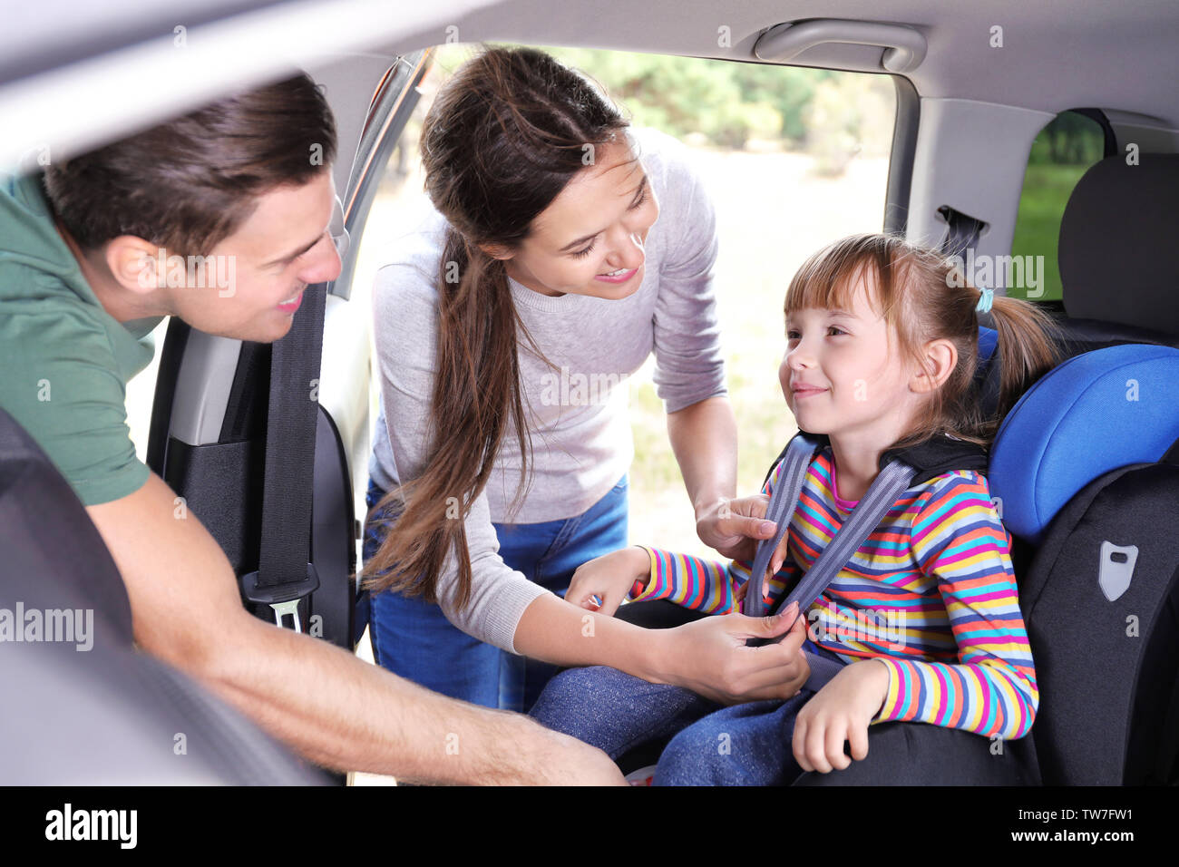 Parents fastening their daughter with car safety belt Stock Photo - Alamy