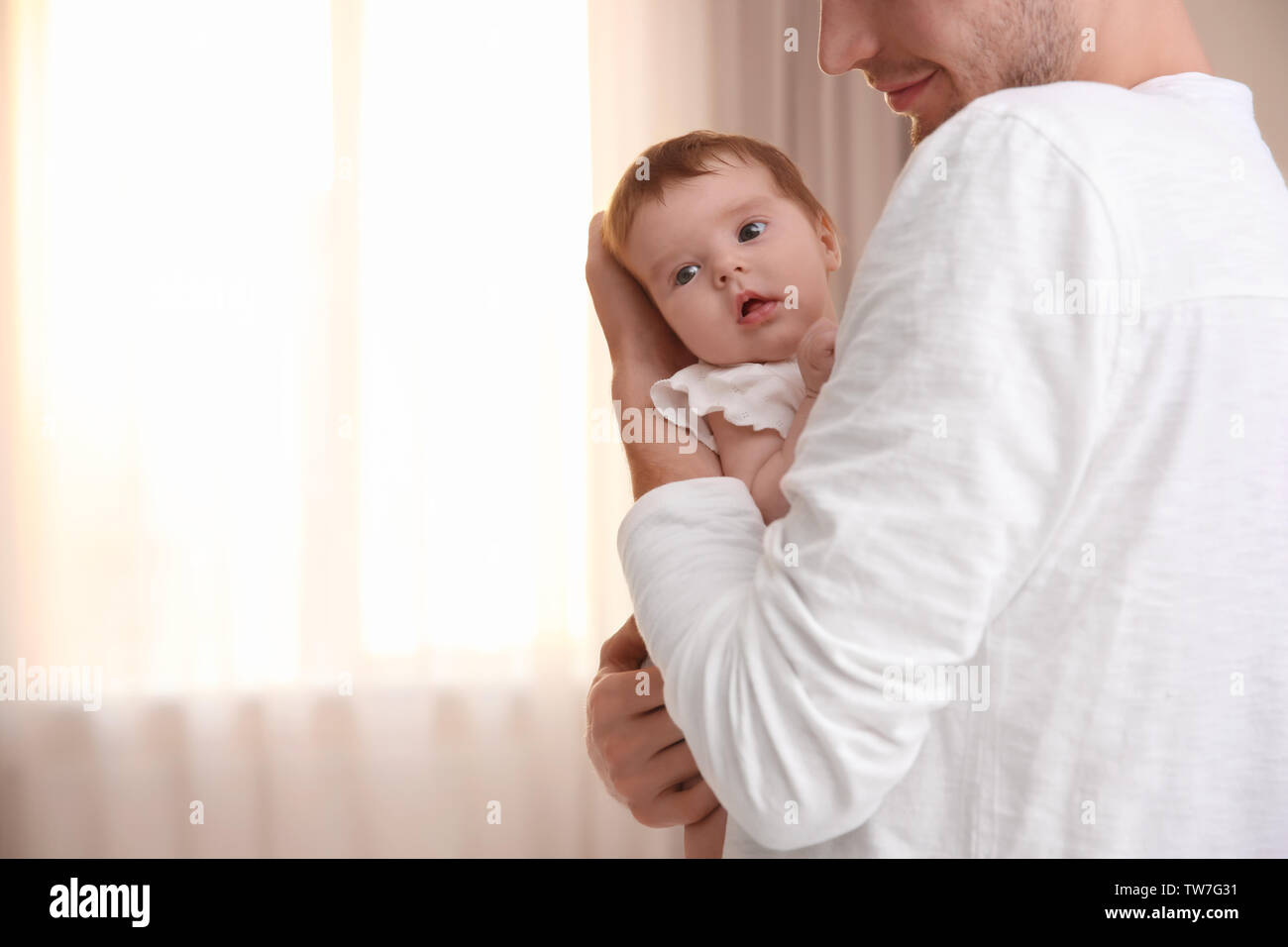 Young father holding baby at home Stock Photo - Alamy
