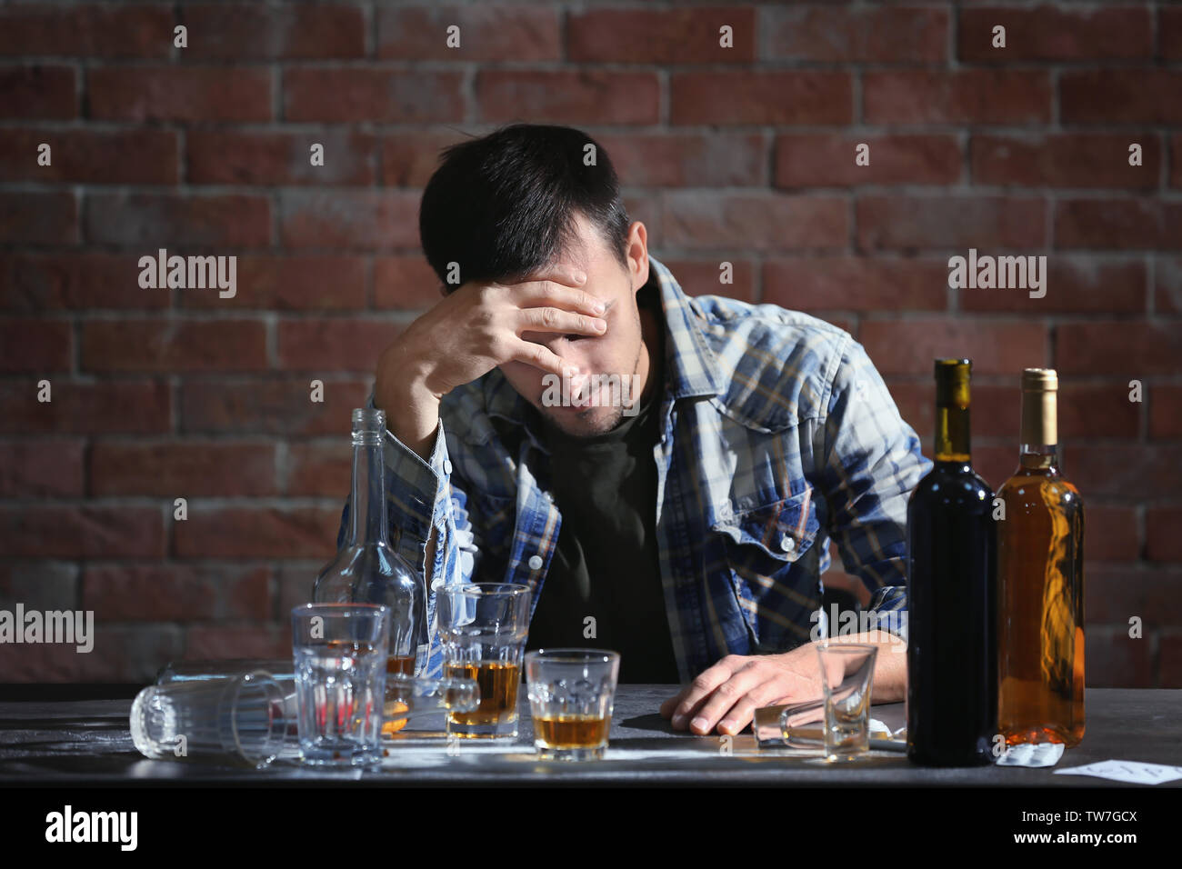 Drunk man sitting at table with alcohol and drugs. Alcoholism concept ...