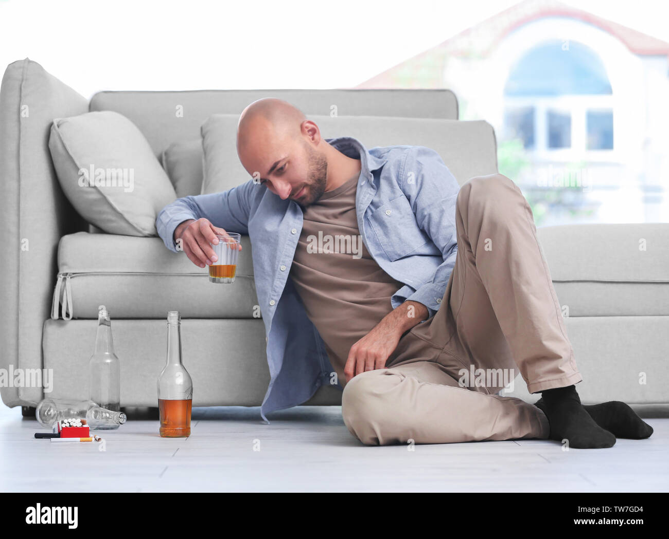 Drunk man sitting on floor at home. Alcoholism concept Stock Photo - Alamy