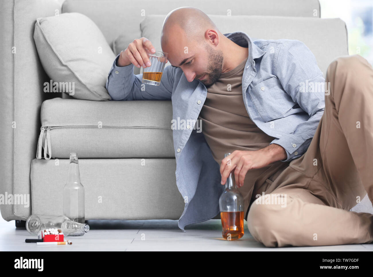 Drunk man sitting on floor at home. Alcoholism concept Stock Photo - Alamy