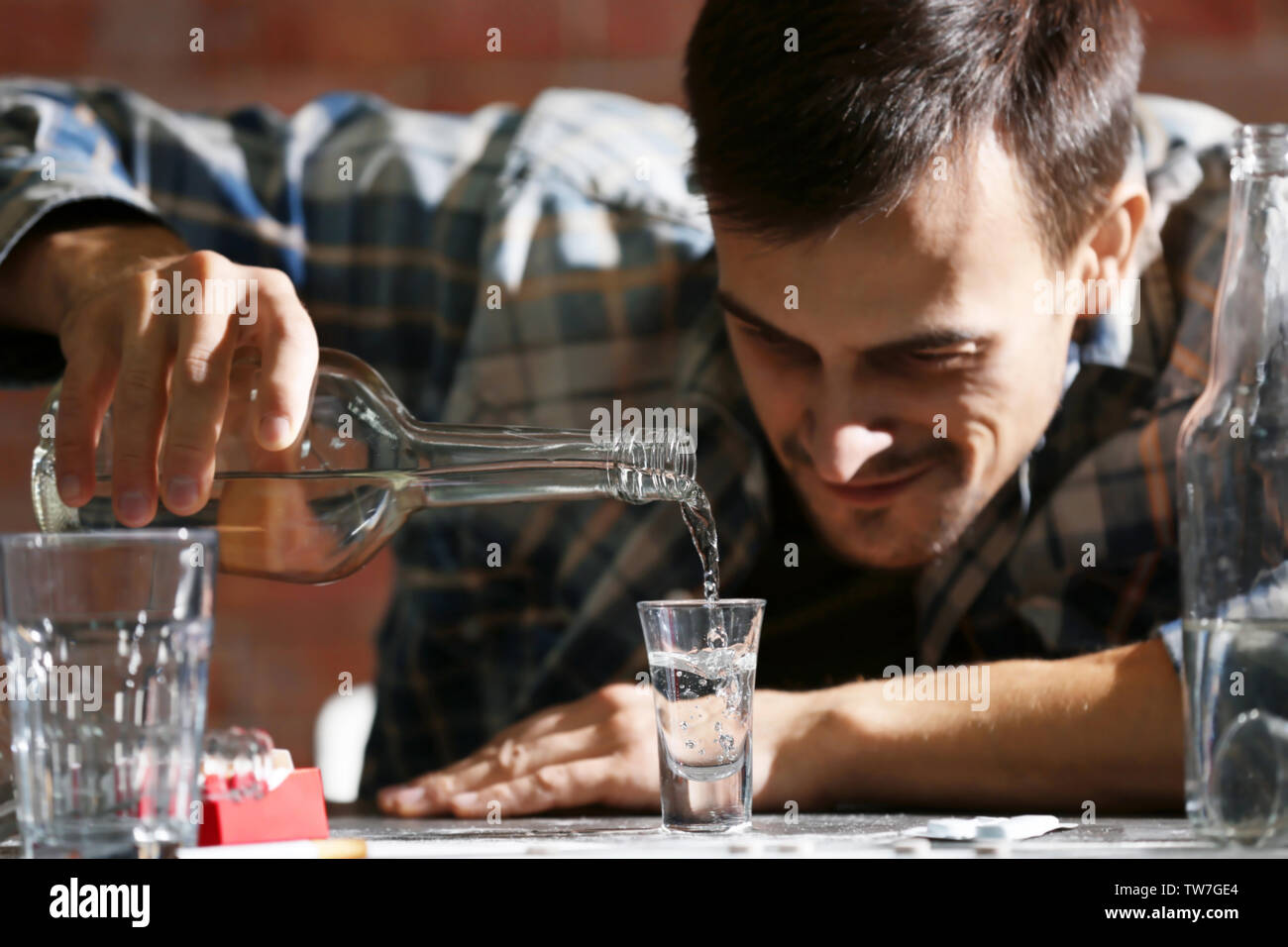 Man sitting at table and pouring alcohol into glass. Alcoholism concept ...