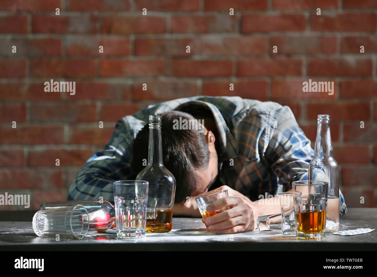 Drunk man at table with alcohol and drugs. Alcoholism concept Stock ...