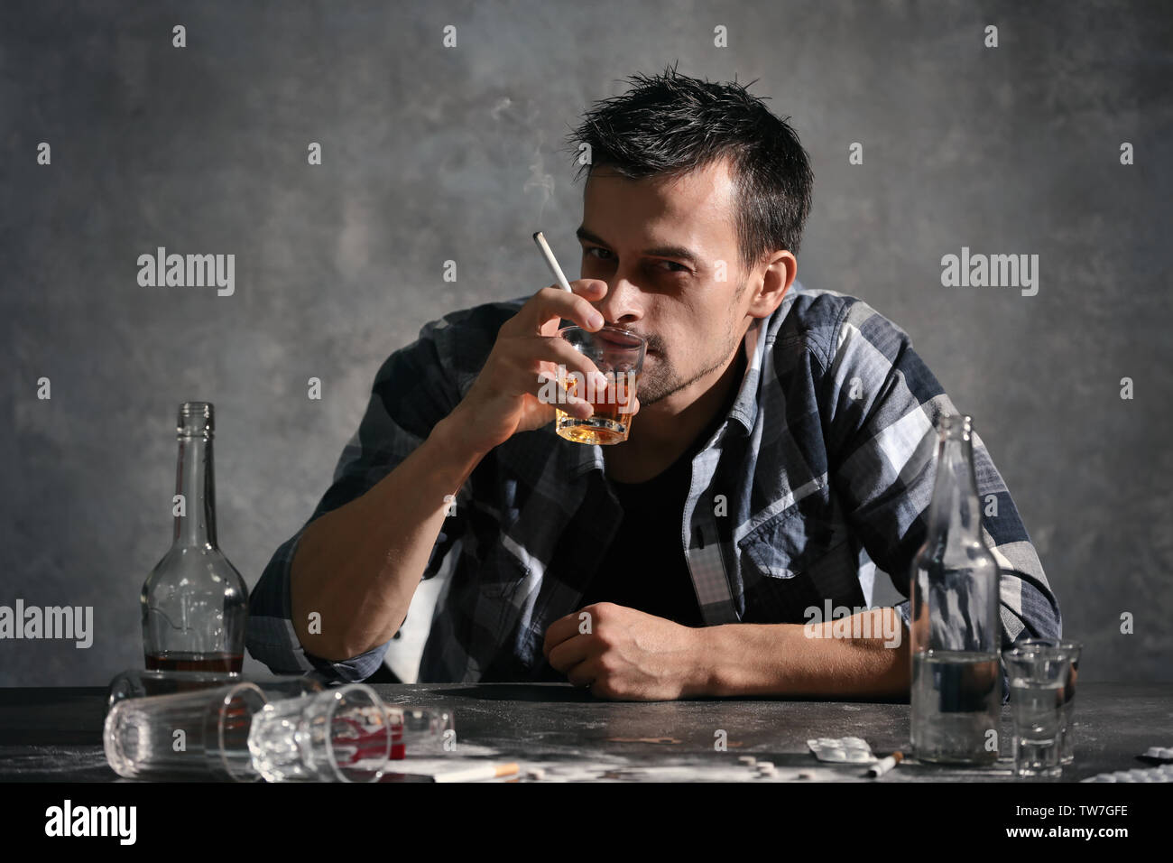 Man drinking alcohol and smoking cigarette while sitting at table Stock ...
