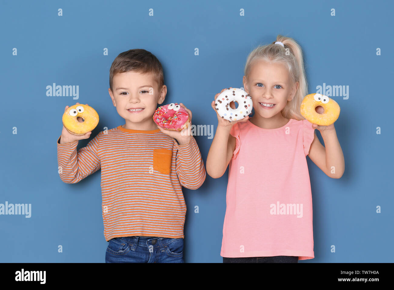 Little children with sweet donuts on color background Stock Photo - Alamy