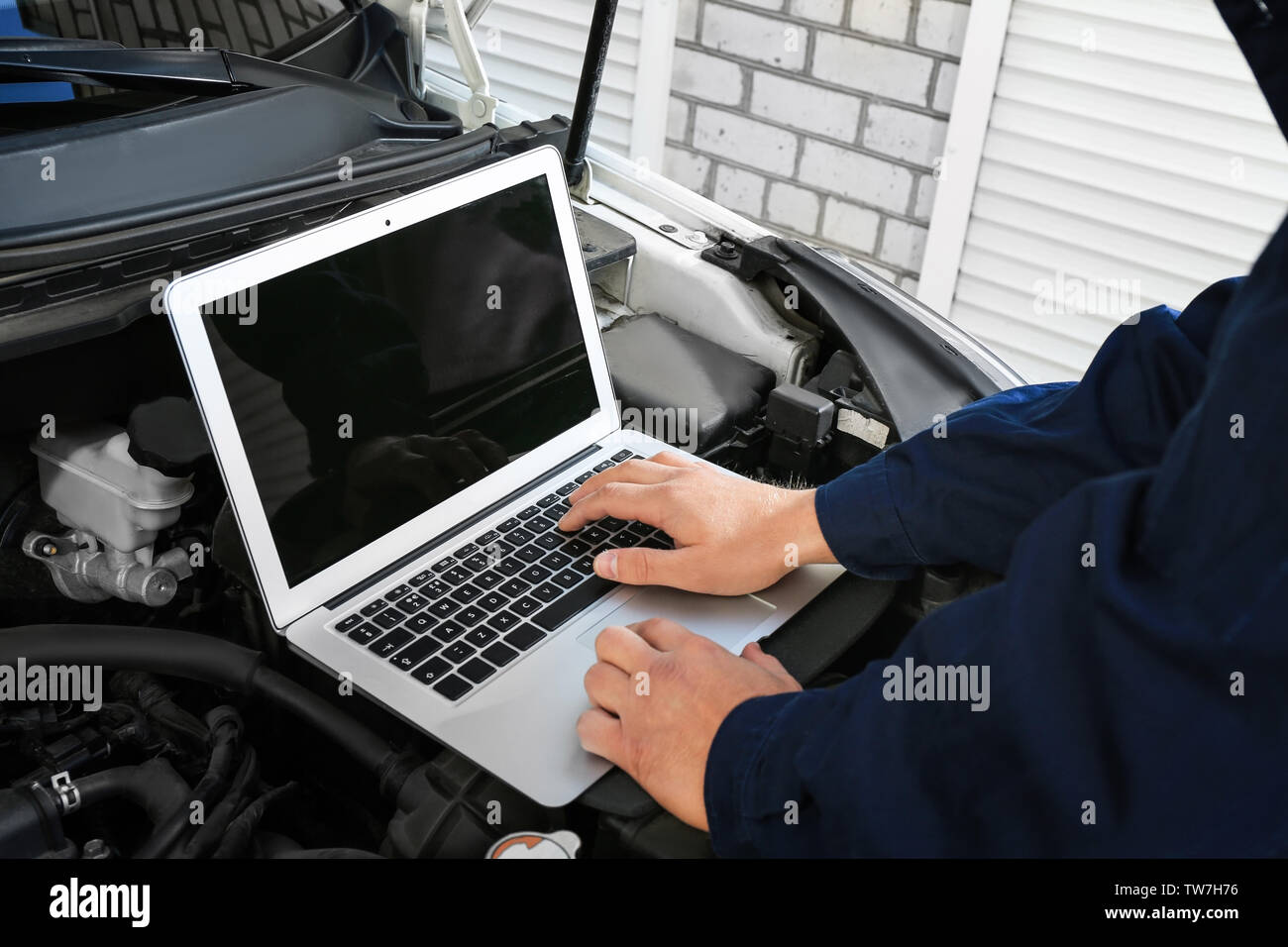 Auto mechanic using computer diagnostic program while repairing car ...