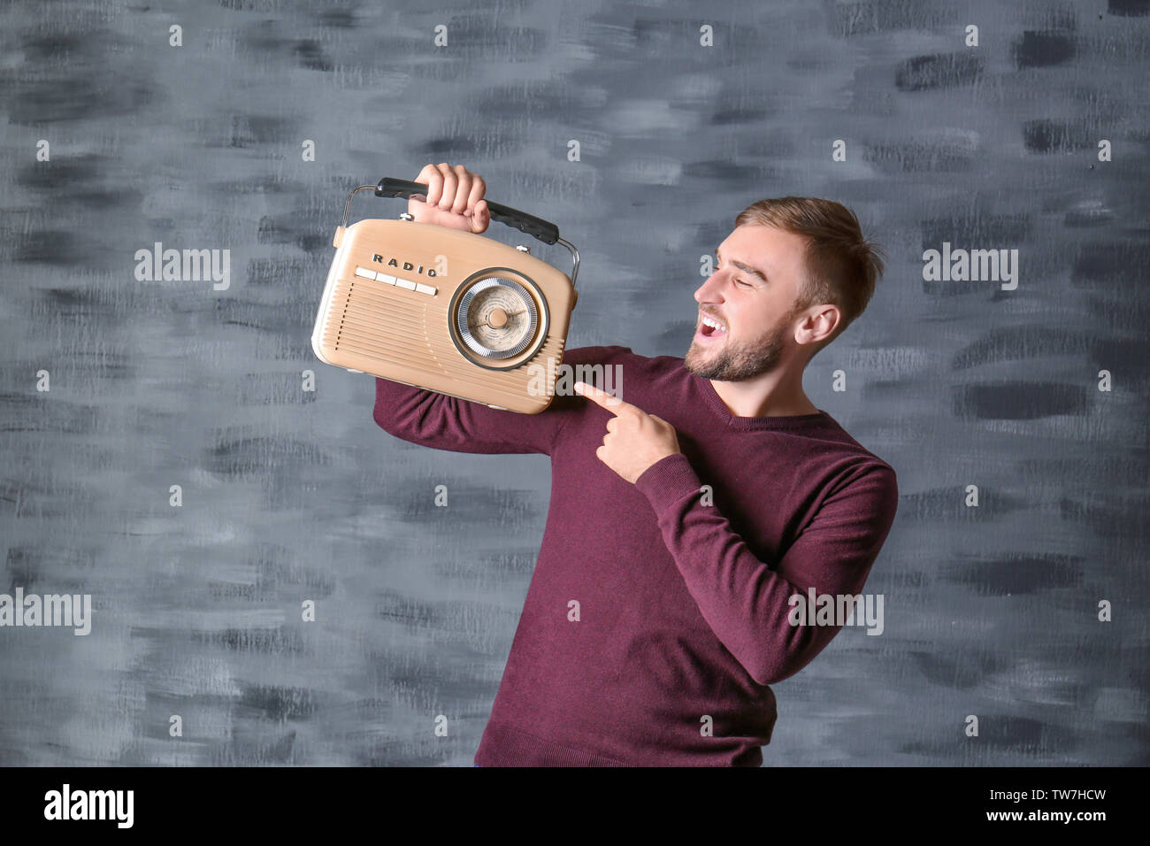 Young man listening to radio against grey background Stock Photo - Alamy