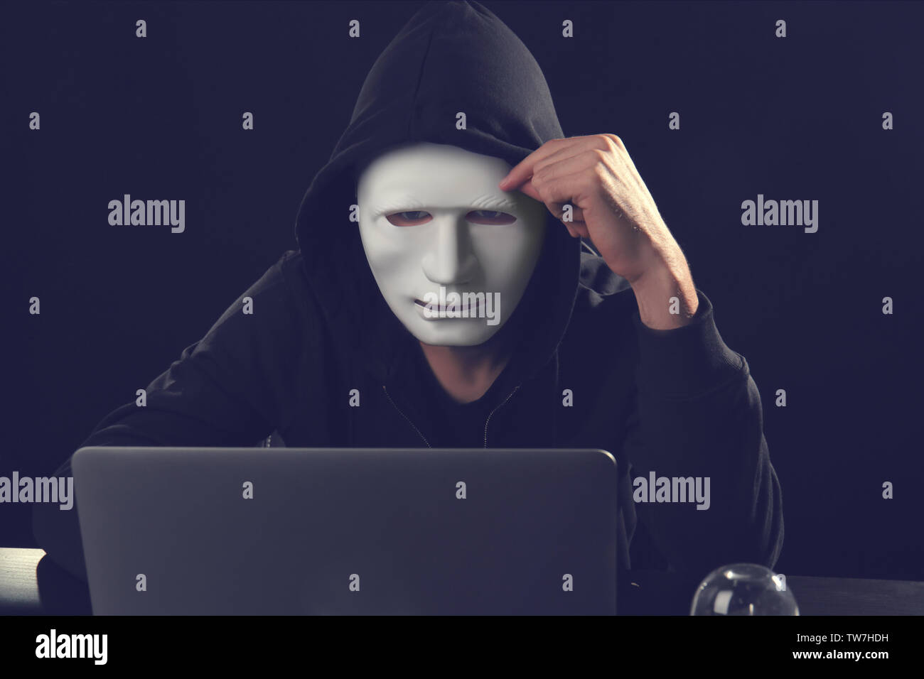 Masked man hacking server in dark room Stock Photo - Alamy