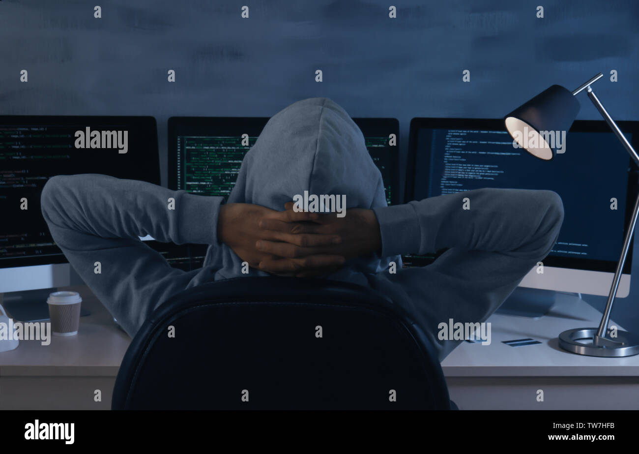 Man wearing hoodie hacking server in dark room Stock Photo - Alamy