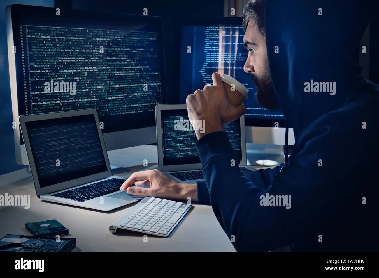 Man drinking coffee while hacking server in dark room Stock Photo - Alamy