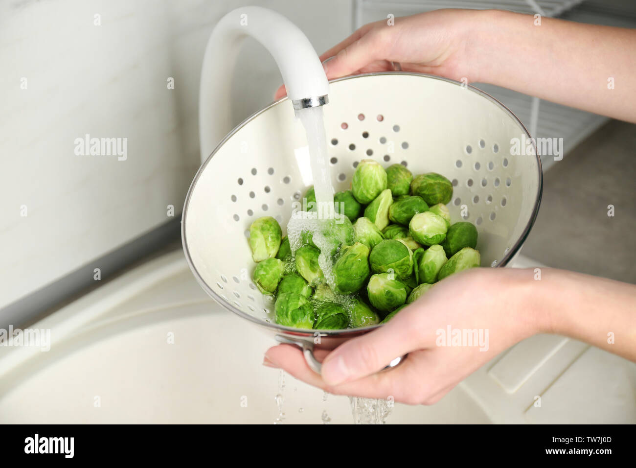 Woman washing raw Brussels sprouts in kitchen sink Stock Photo - Alamy