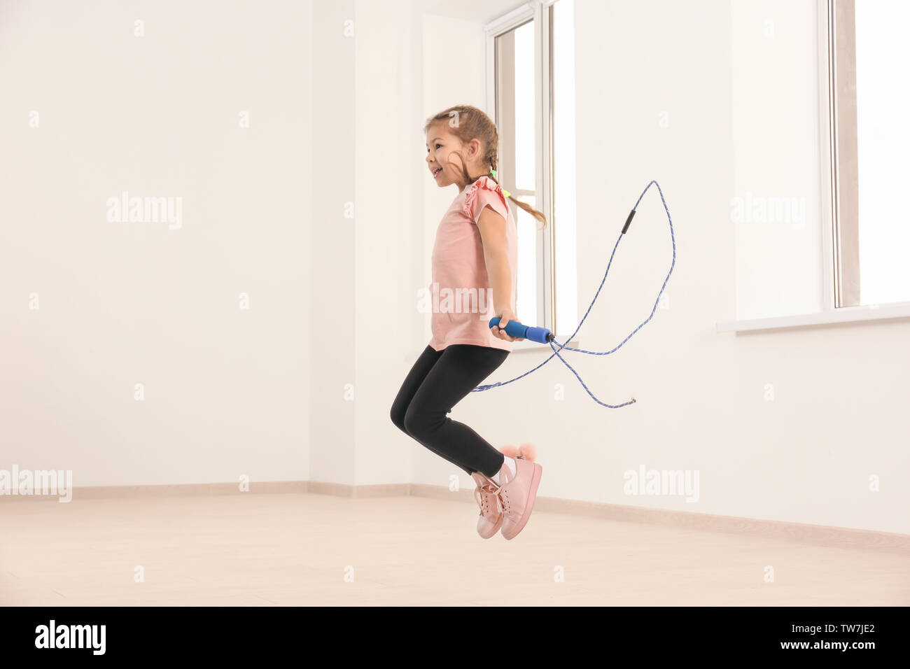 Cute girl skipping rope in light room Stock Photo - Alamy
