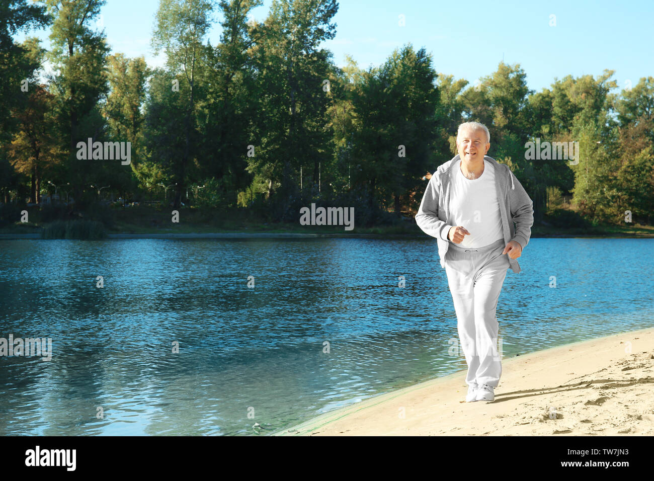 Mature man running near river Stock Photo - Alamy